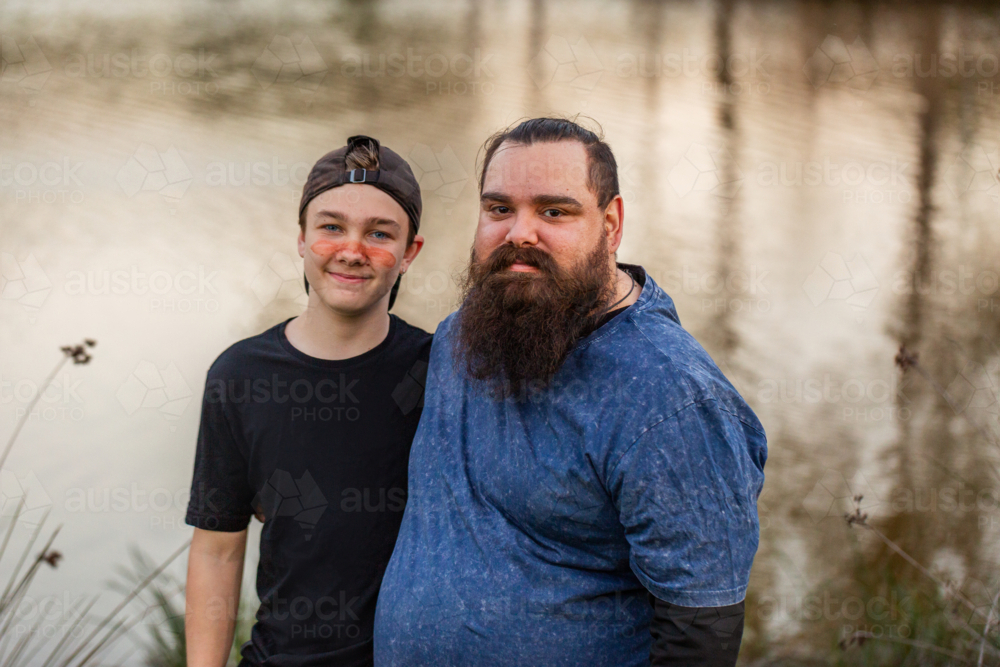 Image of Aboriginal boy and father standing together by waterside at ...
