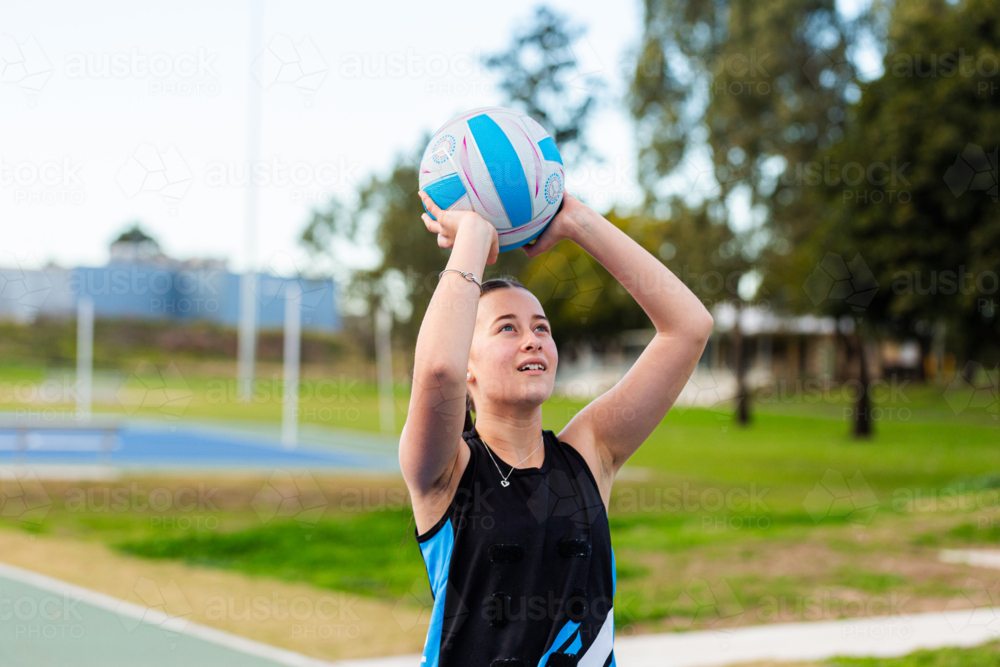 Image of Aboriginal teenager playing netball game shooting for the goal ...