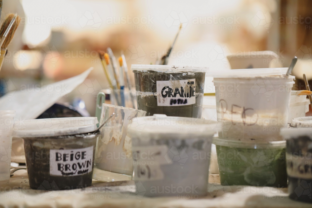 Image of Assorted paint containers and brushes on artist's workspace ...