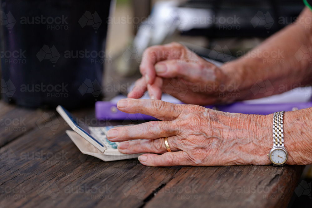 Image of Senor woman’s hands adding up purchase amount at counter of ...