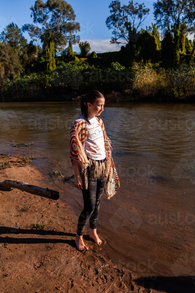 Image of Teen aboriginal girl standing in sunlight by water of inland ...