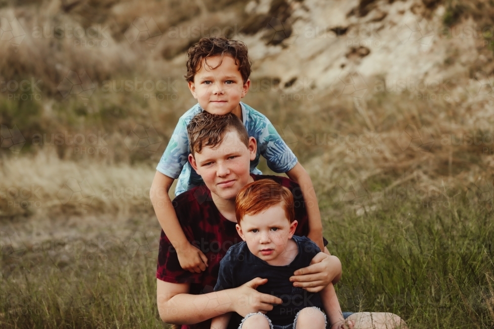 Image of Three brothers sitting together on a rock in the Australian ...